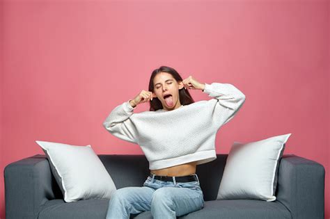 바보 같은 원숭이 얼굴을 불룩하게 만드는 재미있는 장난 어린 소녀는 혀를 보여주는 불룩한 귀를 놀리고 바보 소파에 앉아 여성에