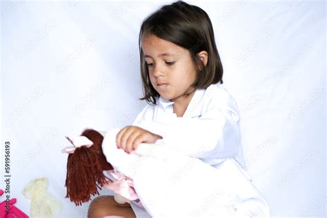 Foto De Criança Com Luva Rosa E Roupa De Medica Brincando De Boneca Com