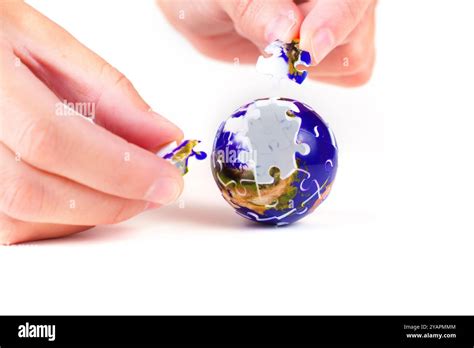 Two Hands Positioning A Puzzle Piece Into A Globe Highlighting The Theme Of Connection And