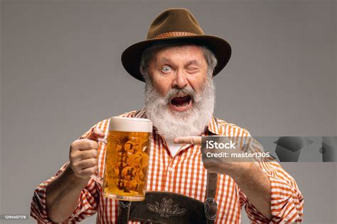 회색 스튜디오 배경에 고립 된 전통적인 오스트리아 또는 바이에른 의상을 입은 행복한 시니어 남자 맥주에 대한 스톡 사진 및 기타