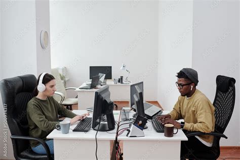 Side View Of Two Young Intercultural Programmers Working In Front Of