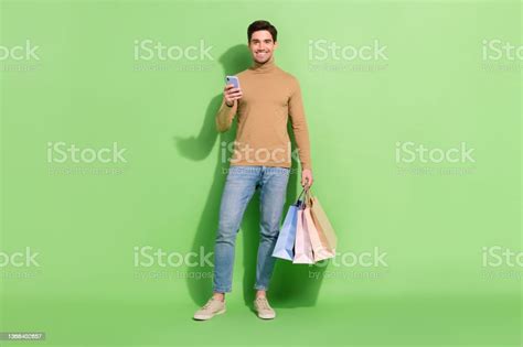 쾌활한 잘생긴 사람의 풀 사이즈 초상화는 녹색 색상 배경에 고립 된 패키지 이빨 미소를 개최합니다 녹색 배경에 대한 스톡 사진