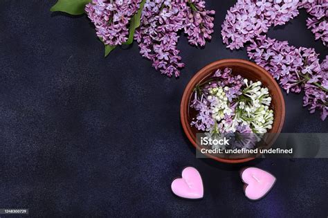 어두운 배경에 나무 그릇에 라일락 꽃에서 향기로운 물로 스파와 웰빙 구성 아로마 테라피와 피부와 바디 케어 플랫 레이 상단 보기