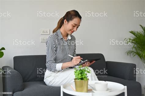 그녀의 녹색 현대 사무실에서 최근 프로젝트에 대한 할 일 목록을 작성하는 웃는 얼굴을 가진 아름다운 인도 아시아인 비즈니스 및