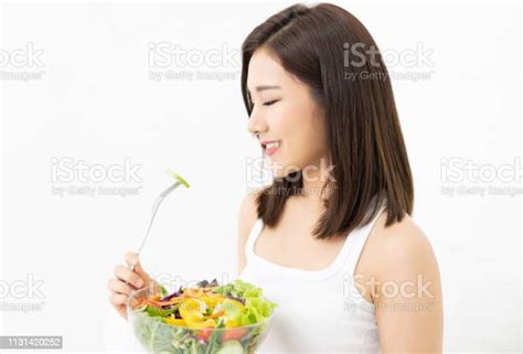 흰색 배경 위에 고립 된 그릇에서 신선한 샐러드를 먹는 아름 다운 젊은 아시아 여자의 초상화 건강 한 음식과 사람들의 개념