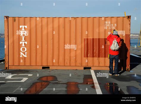 Man In A Red Coat Taking Photographs Of A Red Shipping Container Stock Photo Alamy