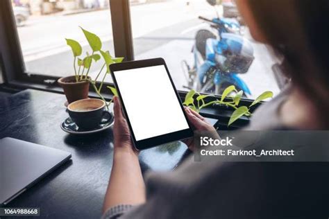 여 자가 들고 빈 흰색 바탕 화면 블랙 태블릿 Pc와 노트북 녹색 잎 커피잔 나무 테이블에 보고의 이랑 이미지 공란에 대한 스톡 사진 및 기타 이미지 Istock
