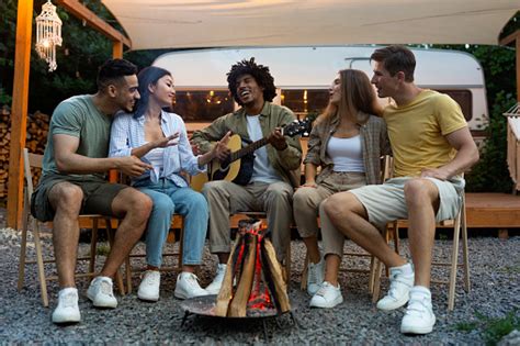 기타를 연주하고 캠프 파이어 근처에서 노래를 부르고 캠핑 밴을 타고 여행하고 여름 휴가를 즐기는 펑키한 다양한 친구들이 밤 하루 시간대에 대한 스톡 사진 및 기타 이미지