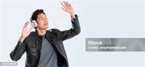세로 스튜디오 음악 가사 개념 Yound 스마트 아시아 아티스트 웨어 스웨터 듣기 헤드폰 행복 분위기 긍정적 인 움직임 눈 닫기 흰색 배경으로 댄스음악 오디오를 즐길 수