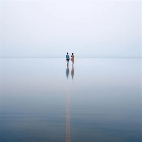 Premium Ai Image Two People Stand In The Water With A Reflection Of A