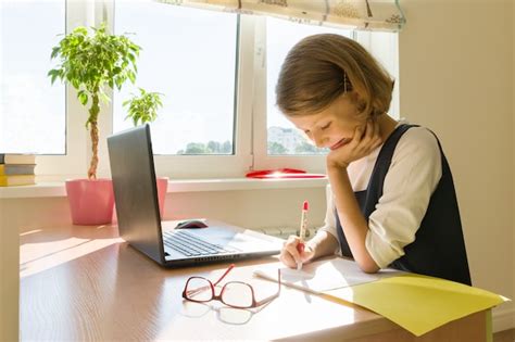 Petite Fille étudiant à La Maison Assise à Table Une écolière écrit