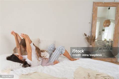 행복한 사랑하는 가족은 함께 침실에서 휴식을 취하고 즐기고 있습니다 어머니와 그녀의 귀여운 유치원 딸 소녀 잠옷에 놀고 아침에 흰색 침대에서 껴안고 행복한 어머니의 날 2