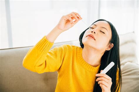 Woman At Home Uses A Rapid Antigen Test Kit Inserting A Swab Into Her