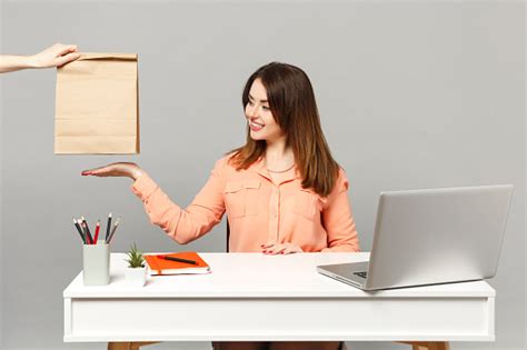 테이크 아웃에 대 한 갈색 맑은 빈 빈 공예 종이 가방에 손을 가리키는 젊은 쾌적 한 여자 회색 배경에 고립 된 Pc 노트북