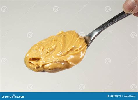 A Swirl Of Peanut Butter On A Spoon About To Be Spread Onto A Bread