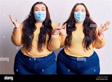 Young Plus Size Twins Wearing Medical Mask Celebrating Crazy And Amazed
