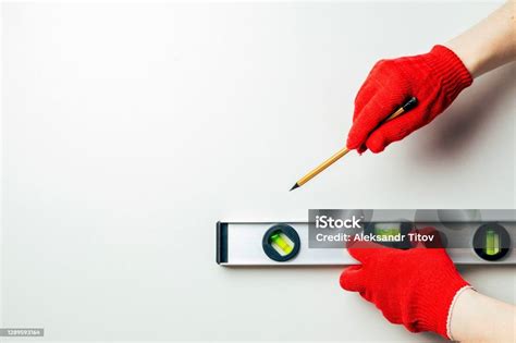 빨간 보호 장갑을 낀 작업자의 손에는 금속 정신 수준과 흰색 벽에 연필이 있습니다 Diy에 대한 스톡 사진 및 기타 이미지