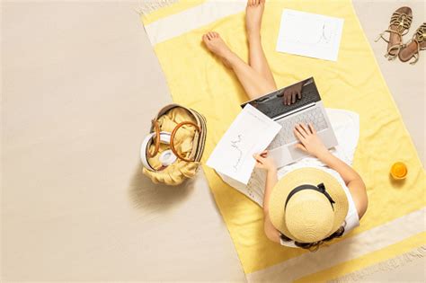 사업가 프리랜서 는 모래 해변의 비치 타월에 앉아 그래픽과 차트와 노트북에서 작업 주스를 마시는 여름 방학 공중 보기 공중 뷰에