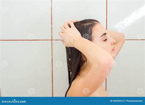 Portrait Of A Young Brunette Who Is Standing Under The Shower With Wet