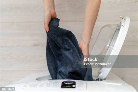 그녀의 손에 부드러운 건조 섬유를 들고 여자의 자른 사진 그녀는 밝은 아파트 빛 내부에 흰색 세탁기에서 세탁 과정을 완료