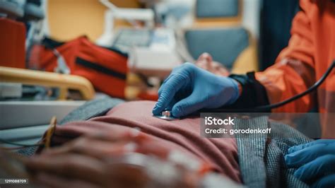 의료 병원으로 가는 길에 부상당한 환자에게 의료 도움을 제공하는 Ems 전문 구급대원의 샷을 닫습니다 구급차에서 청진기를 사용하여 응급 치료 도우미 20 24세에 대한 스톡