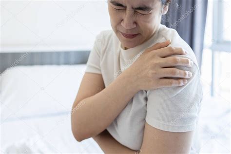 Mujer asiática de mediana edad que sufre de dolor en el hombro