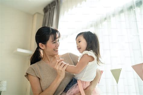 아시아의 아름다운 사랑하는 어머니는 어린 여자 딸을 팔에 안고 빙글빙글 돌고 있습니다 매력적인 부모는 어린 작은 소녀와 미소