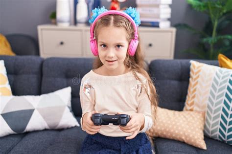 Adorable Caucasian Girl Playing Video Game Sitting On Sofa At Home