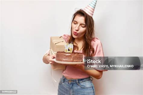 소녀는 축제 케이크를 들고 숫자 19의 형태로 촛불을 불고 있습니다 생일 축하의 개념입니다 18에 대한 스톡 사진 및 기타