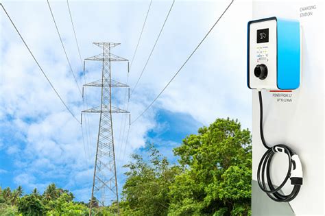 녹색 나무 배경으로 자연적인 파란 하늘과 고전압 전기 폴란드에 전기 차 충전 또는 잡종 차를 위한 현대 Ev 역 플러그 및 전원 케이블 공급 연료 및 전력 생산에 대한 스톡