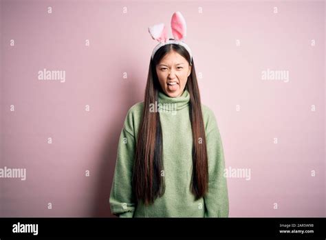 Young Asian Woman Wearing Cute Easter Bunny Ears Over Pink Background