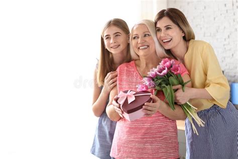 Ung Kvinna Med Dottern Som Hemma Gratulerar Den Mogna Familjemedlemmen Arkivfoto Bild Av Mamma