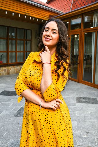 패션 블로거 화려한 노란색 드레스 드레스를 입고 소녀 패션 블로그 사진 촬영 긴 머리 서 카메라를보고 갈색 머리 사업가 성공