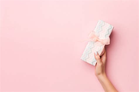 살아있는 산호 배경에 컬러 리본 줄무늬 선물 상자를 들고 여성의 손 크리스마스 컨셉 이나 다른 휴일 핸드메이드 선물 상자 카피