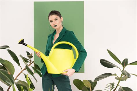 아름 다운 세련 된 여 자가 물을 들고 수 카메라를 보고 포즈 배경에 식물과 바다 녹색 노랑에 대한 스톡 사진 및 기타 이미지 노랑 녹색 물뿌리개 Istock