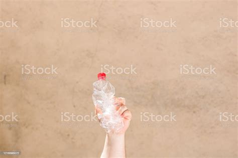 손으로 들고 흐린 배경에 고립 된 빈 플라스틱 병을 박살 재활용 및 자원 봉사 개념 환경 오염 및 전 세계 생태 문제 개념에