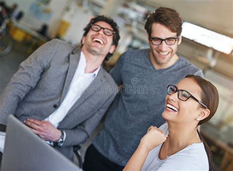 Success Keeps Them Upbeat Laughing Colleagues Working Together On A Laptop In A Modern Office
