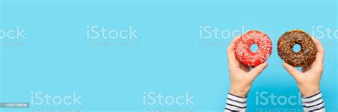 여성의 손은 파란색 배경에 도넛을 들고 있습니다 컨셉 제과 점 패스트리 커피 숍 배너 플랫 레이 상단 보기 도넛에 대한 스톡