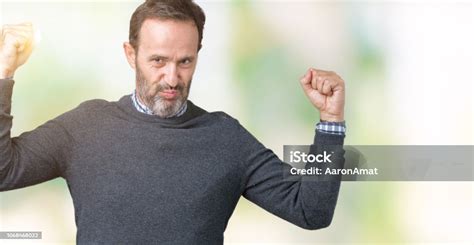 잘생긴 중 년 수석 남자 팔 근육 자랑 웃 고 보여주는 격리 된 배경 위에 스웨터를 입고 피트 니스 개념입니다 개념에 대한 스톡