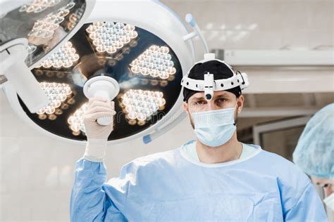 Male Surgeon Is Holding Light Lamp In The Operating Room And Directs It
