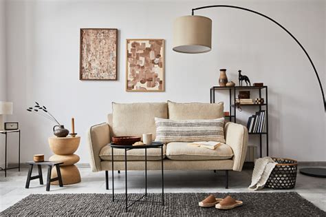 모의 포스터 프레임 베이지 색 소파 사이드 테이블 메탈 선반에 세련된 작은 개인 액세서리와 현대 거실 인테리어의 창조적 인 구성 공간을 복사합니다 템플렛 모델하우스 내부에