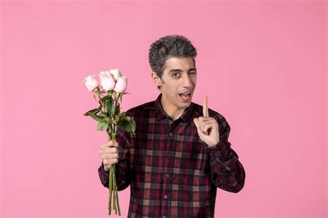 Jovem Do Sexo Masculino Segurando Lindas Rosas Cor De Rosa Na Parede