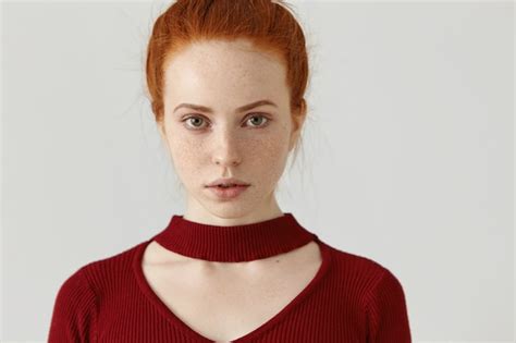 Рыжая кавказская девушка с красивым лицом с веснушками в модном красном