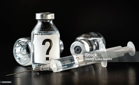 피하 주사기 바늘이 가까운 백신 병 라벨에 물음표 검은 색 배경 실험 치료 개념의 알려지지 않은 부작용 물음표에 대한 스톡 사진