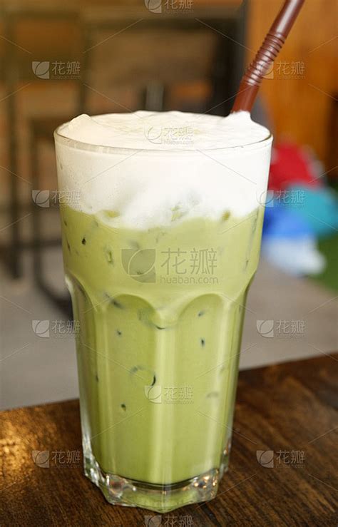 牛奶泡沫绿茶 冰绿茶玻璃杯冰抹茶拿铁冰沙和稻草在咖啡店桌上