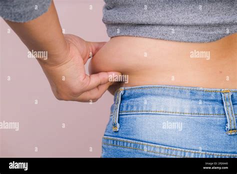 Fat Woman Hand Holding Excessive Belly Fat Isolated On Pink Background