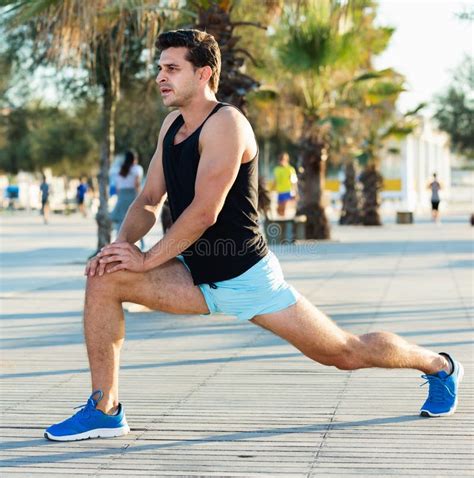 Physically Fit Man Doing Stretching Exercises On Morning Beach Stock