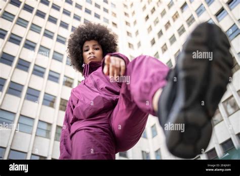 Afro Young Woman With Blank Expression Standing Against Built Structure