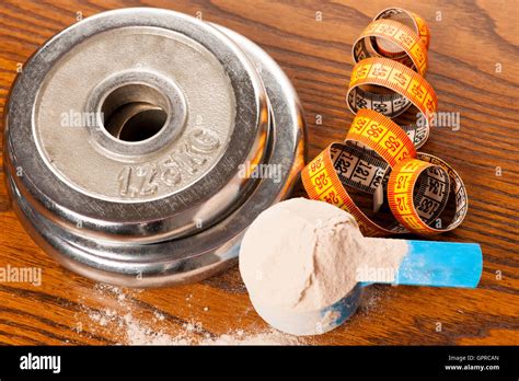 Whey Protein Powder In Measuring Scoop Meter Tape And Dumbbell On