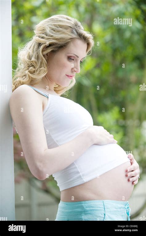 Pregnant Female Wavy Blonde Hair Wearing A White Vest And Blue